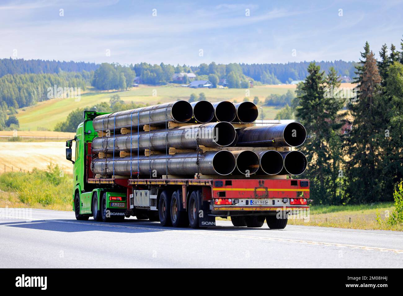Lime green Scania truck in front of semi trailer hauls metallic pipes ...