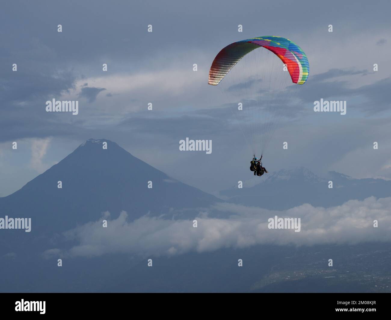 two people paragliding with mountains in the background Stock Photo - Alamy