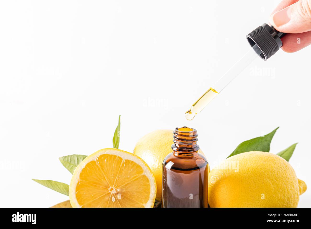 the fingers of a woman's hand hold a pipette with a lemon cosmetic over ...