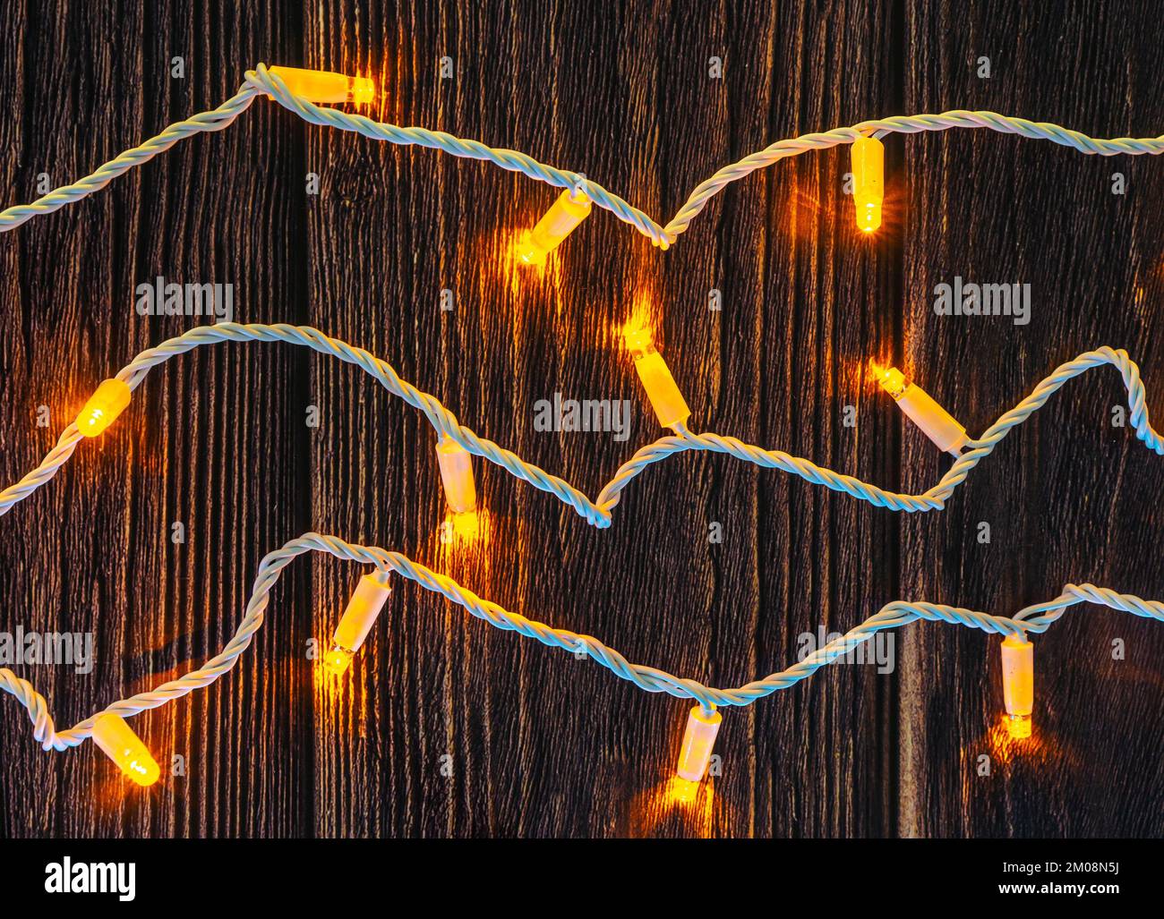 Christmas garland with yellow leds and white wire on dark wood board ...