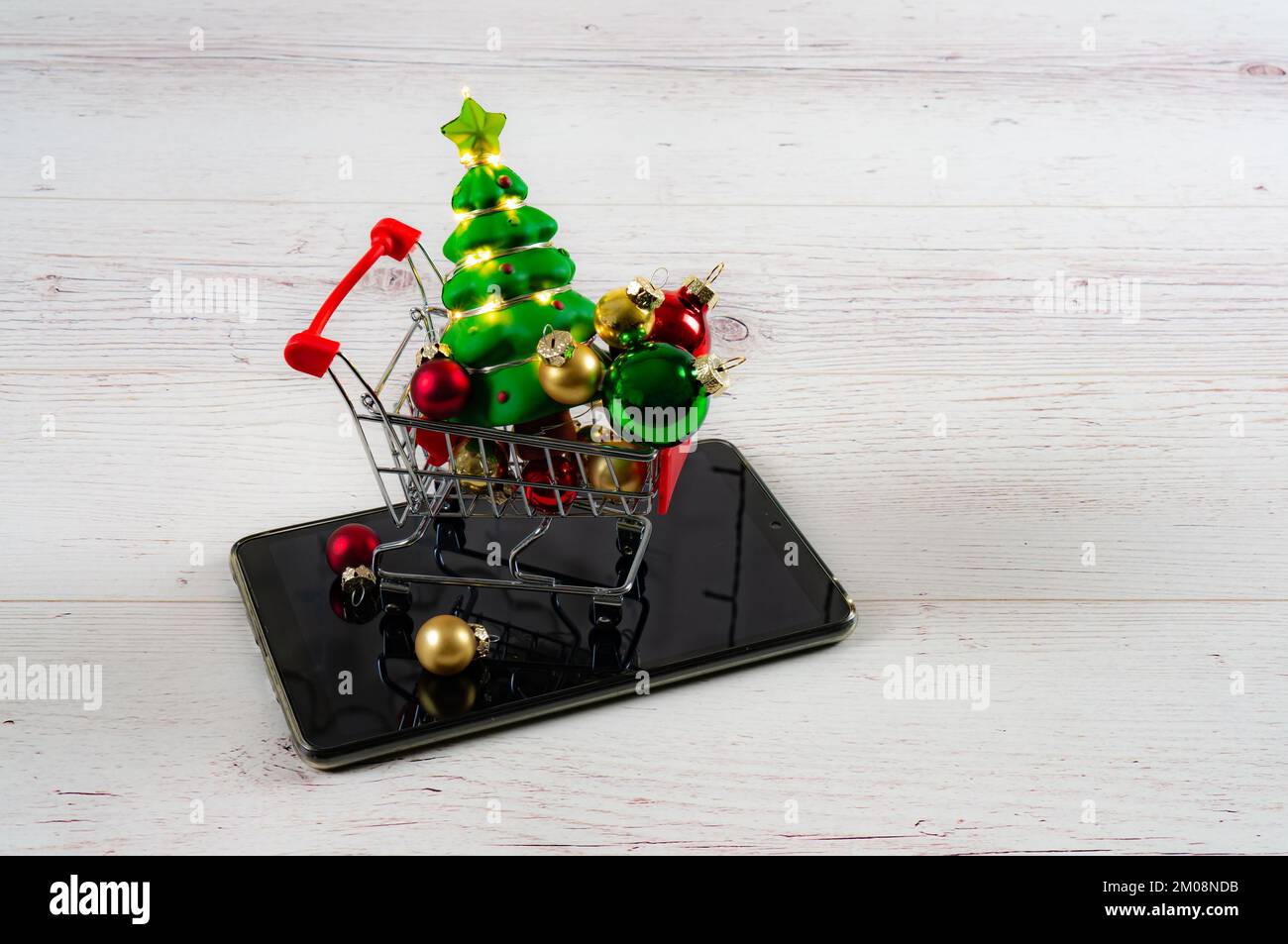 Shopping trolley with christmas balls and tree with garlands on the ...