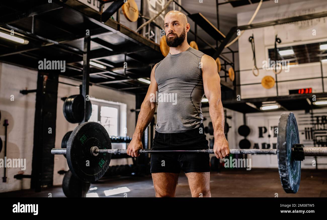 A portrait of a male weightlifter in sportswear. He does barbell ...