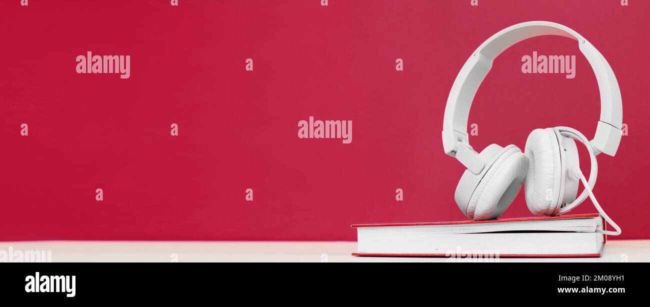 Audio book concept with modern white headphones and hardcover book on a ...
