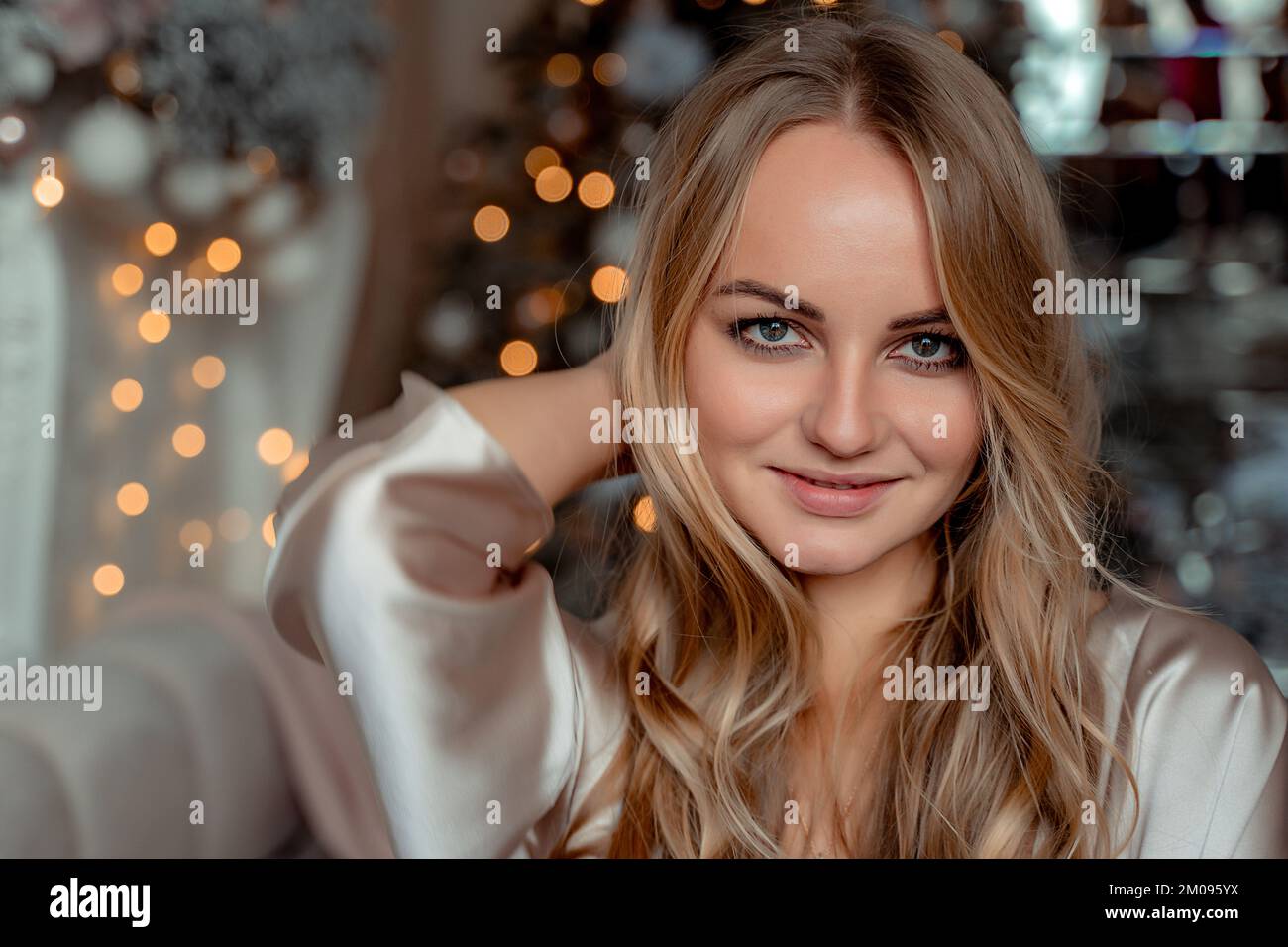 Portrait of a young blonde sitting on a sofa in pajamas. The room is ...
