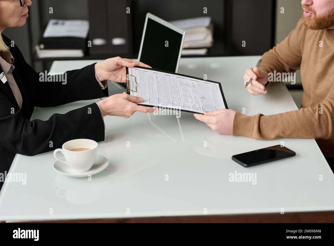 Side view closeup of insurance advisor handing application form to ...