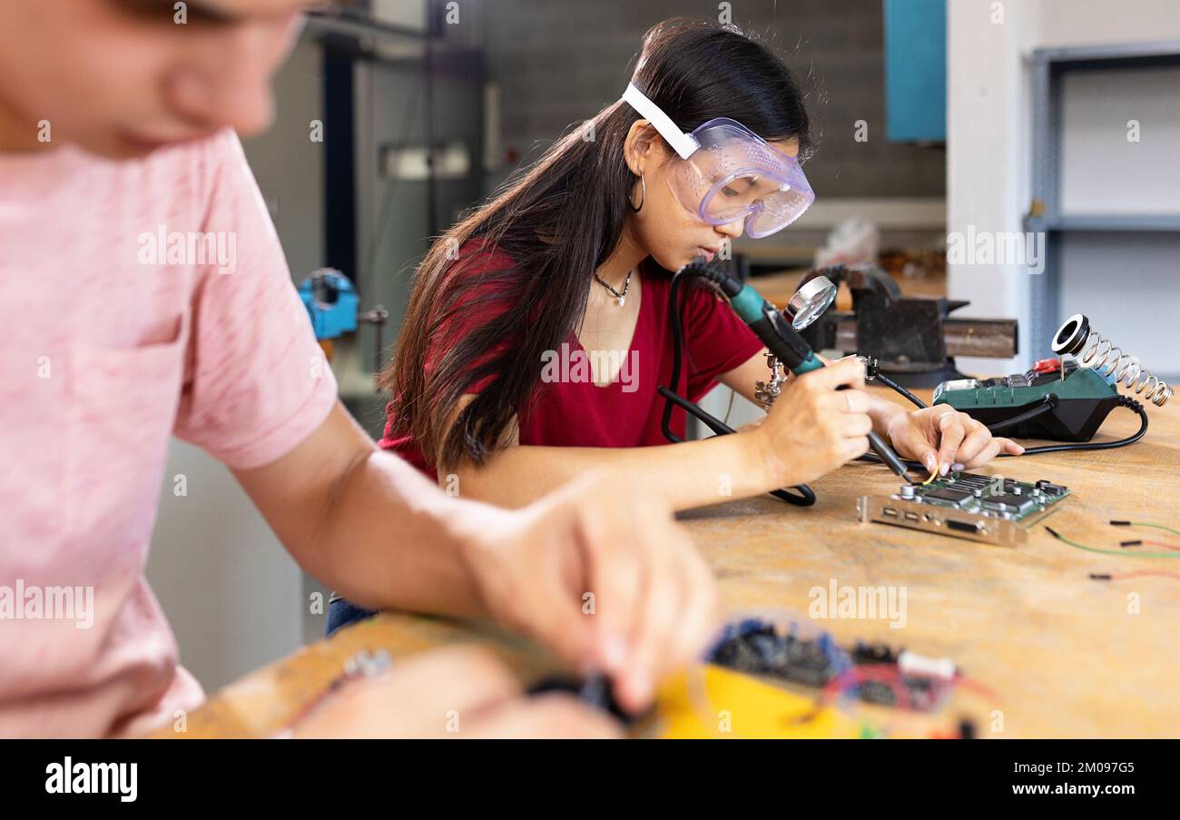 Young asian female student building robot in engineering class at high ...