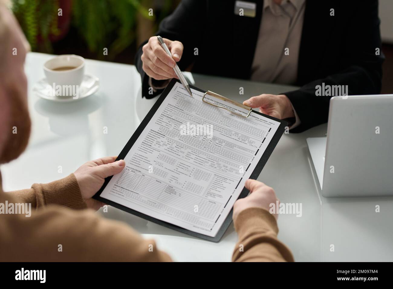 Closeup of insurance advisor handing application form to client during ...