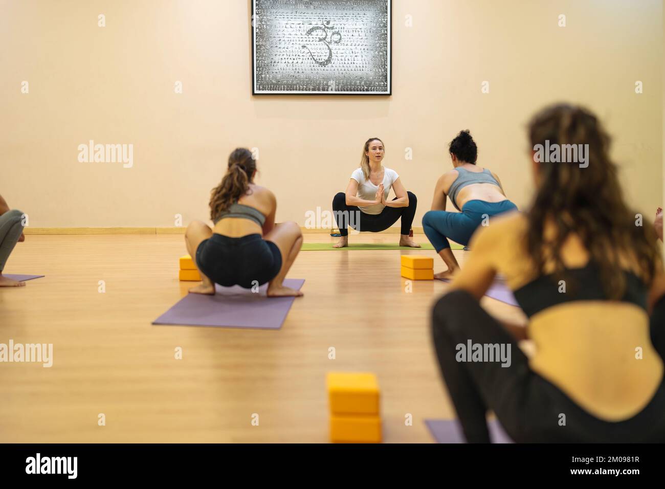 caucasian teacher teaching yoga classes in malasana pose Stock Photo ...