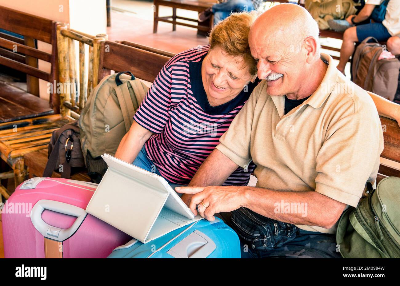 Happy senior couple sitting with digital laptop and travel baggage ...