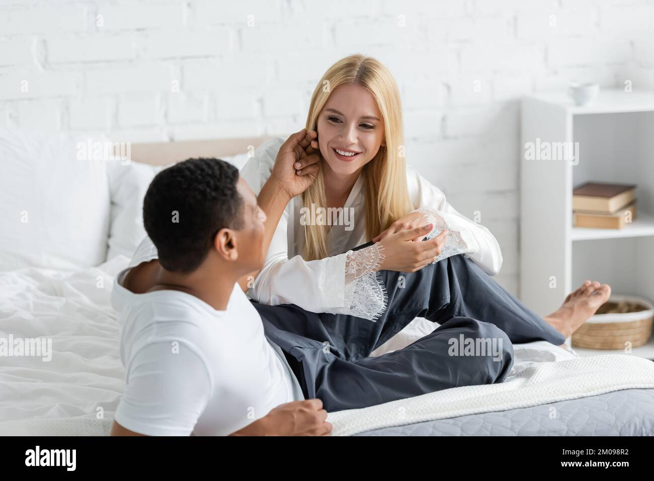 african american man in pajama pants touching face of young girlfriend ...
