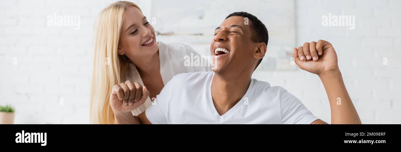 excited african american man with closed eyes laughing near smiling ...