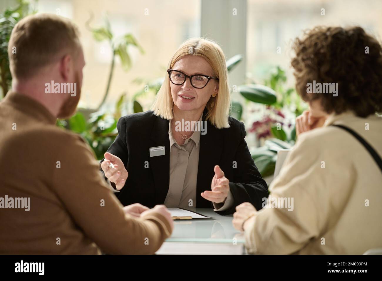Portrait of female insurance broker consulting couple in agency and ...