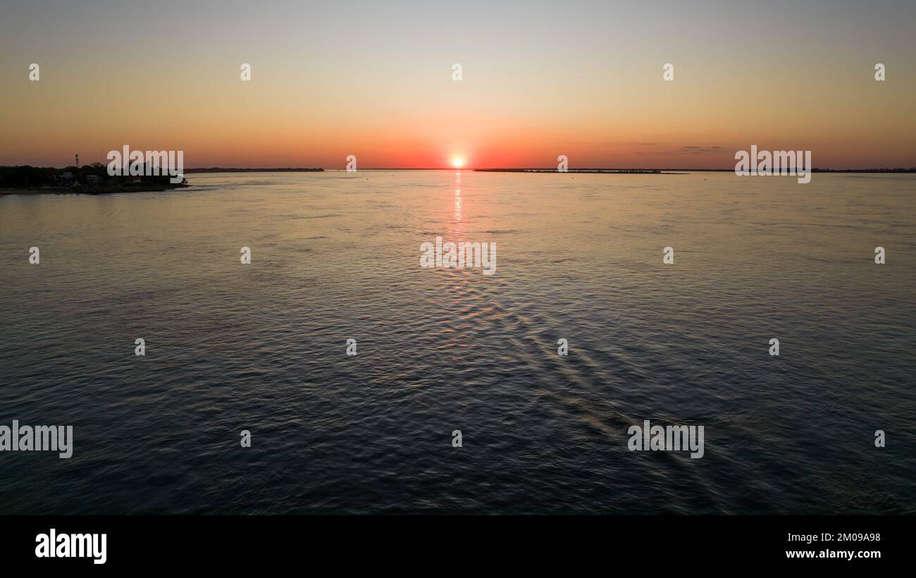 A beautiful warm sunset over the river and a piece of land in distance ...