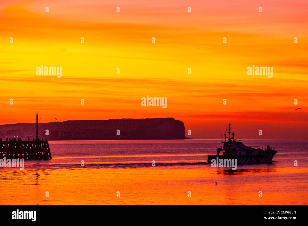 A sunrise over Seaford Bay with a fishing boat in East Sussex, England ...