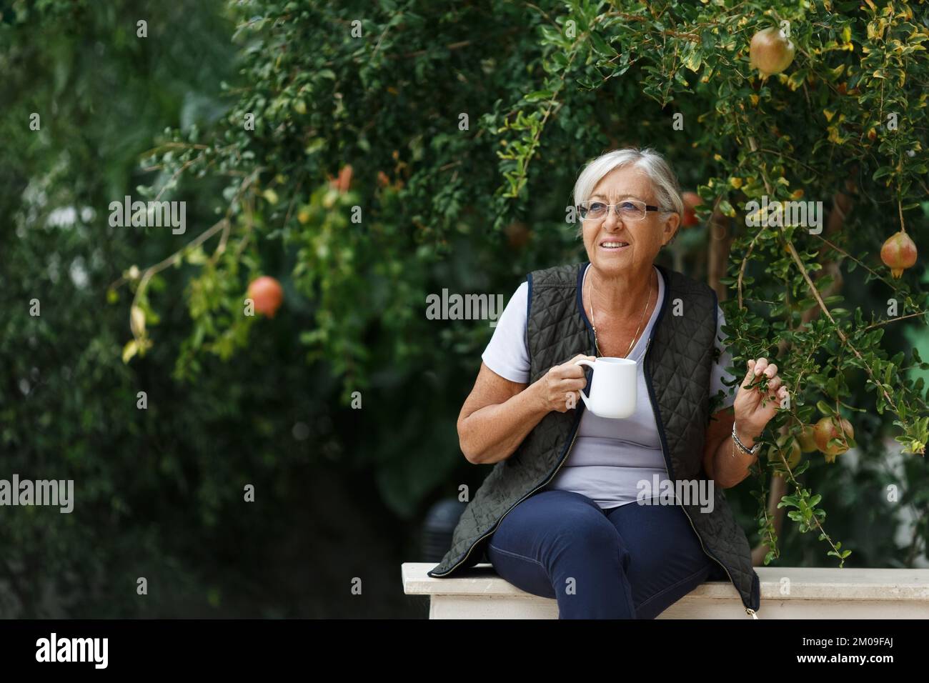 Senior grey hair woman having tea in sunny garden stunning countryside ...