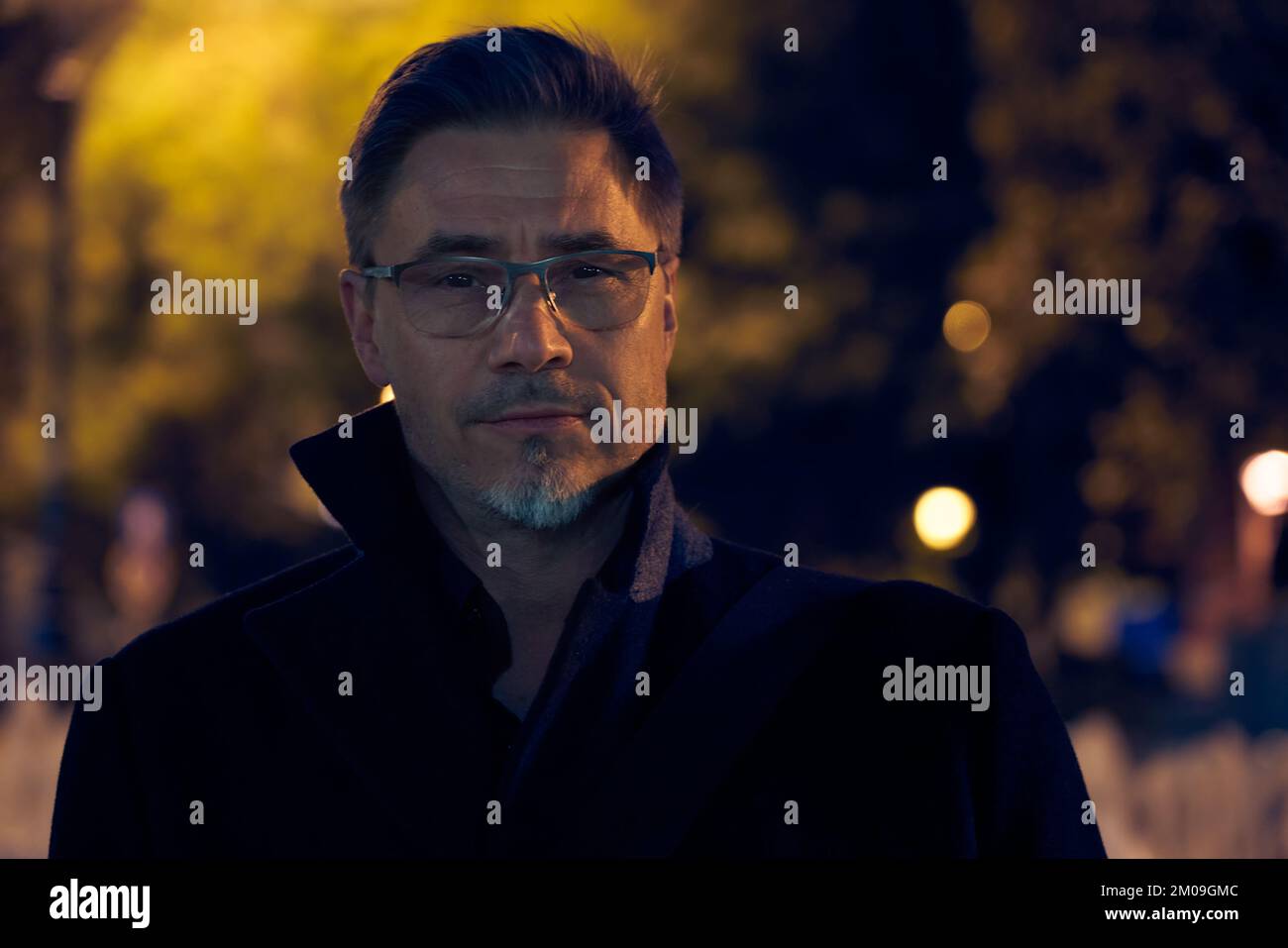 Mid adult man on the street at night wearing black coat. Mature age ...