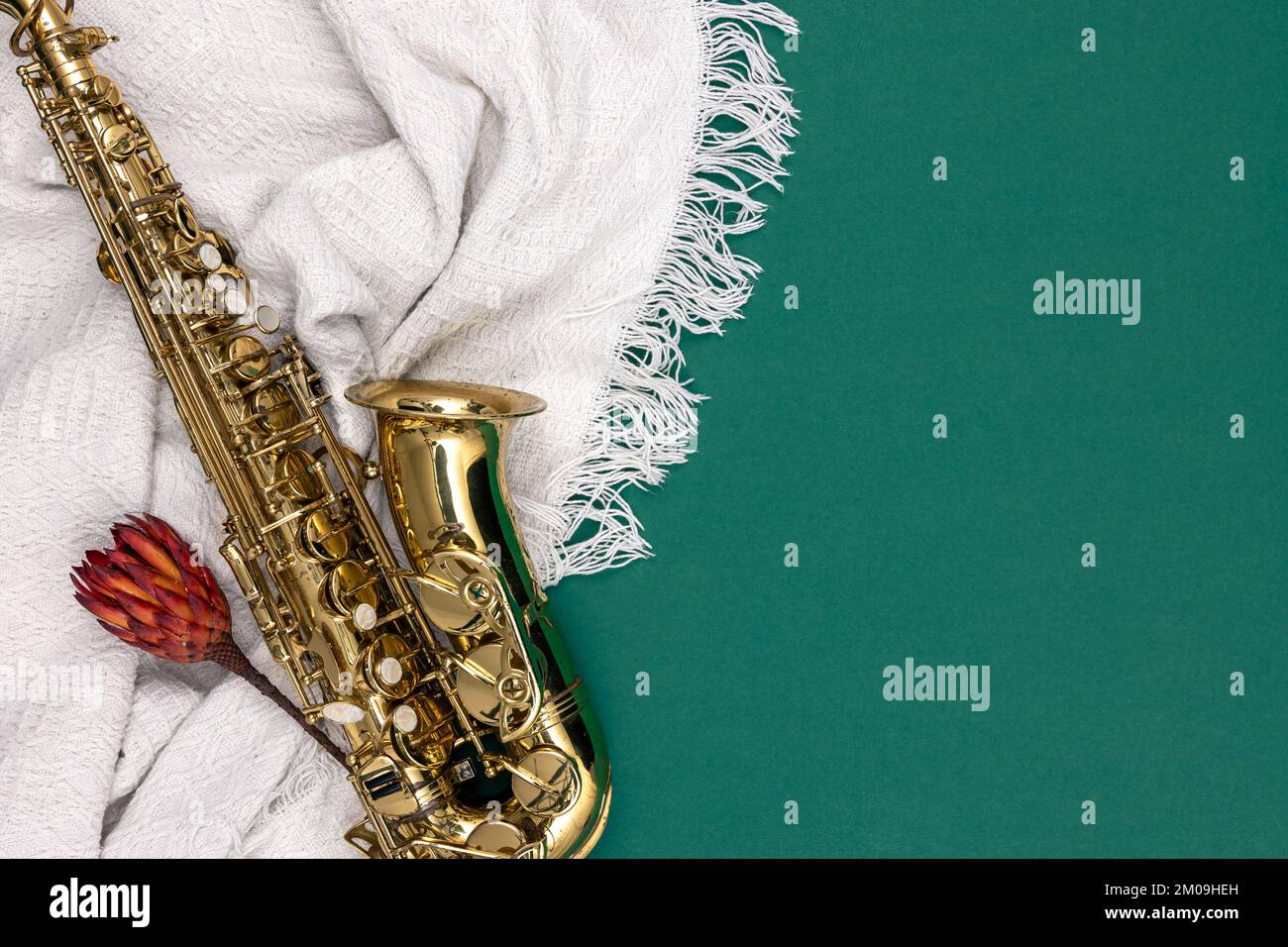 Saxophone on a green background with a blanket and a flower, top view ...