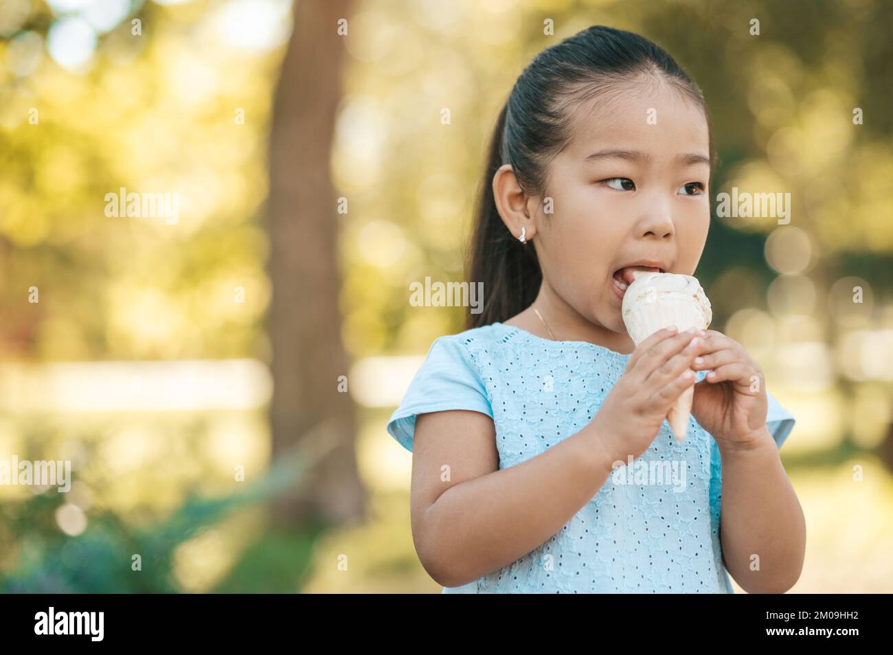 Cute little girl eating ice-cream and looking contented Stock Photo - Alamy
