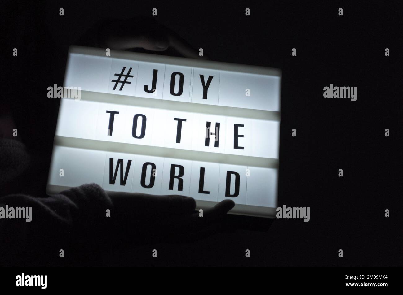 Light box being held with the phrase, "# Joy to the world" illuminated ...