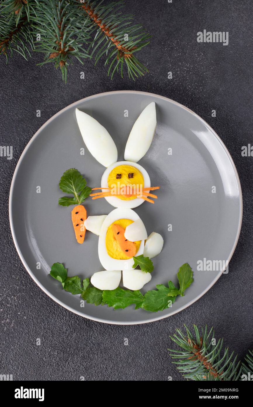 Funny rabbit made from boiled eggs, peeled carrots and arugula on gray ...