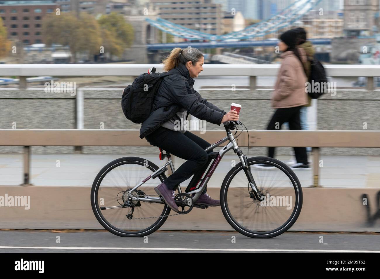 A woman commuting on an e-bike across London Bridge, London, UK. 17 Nov 2022 Stock Photo - Alamy
