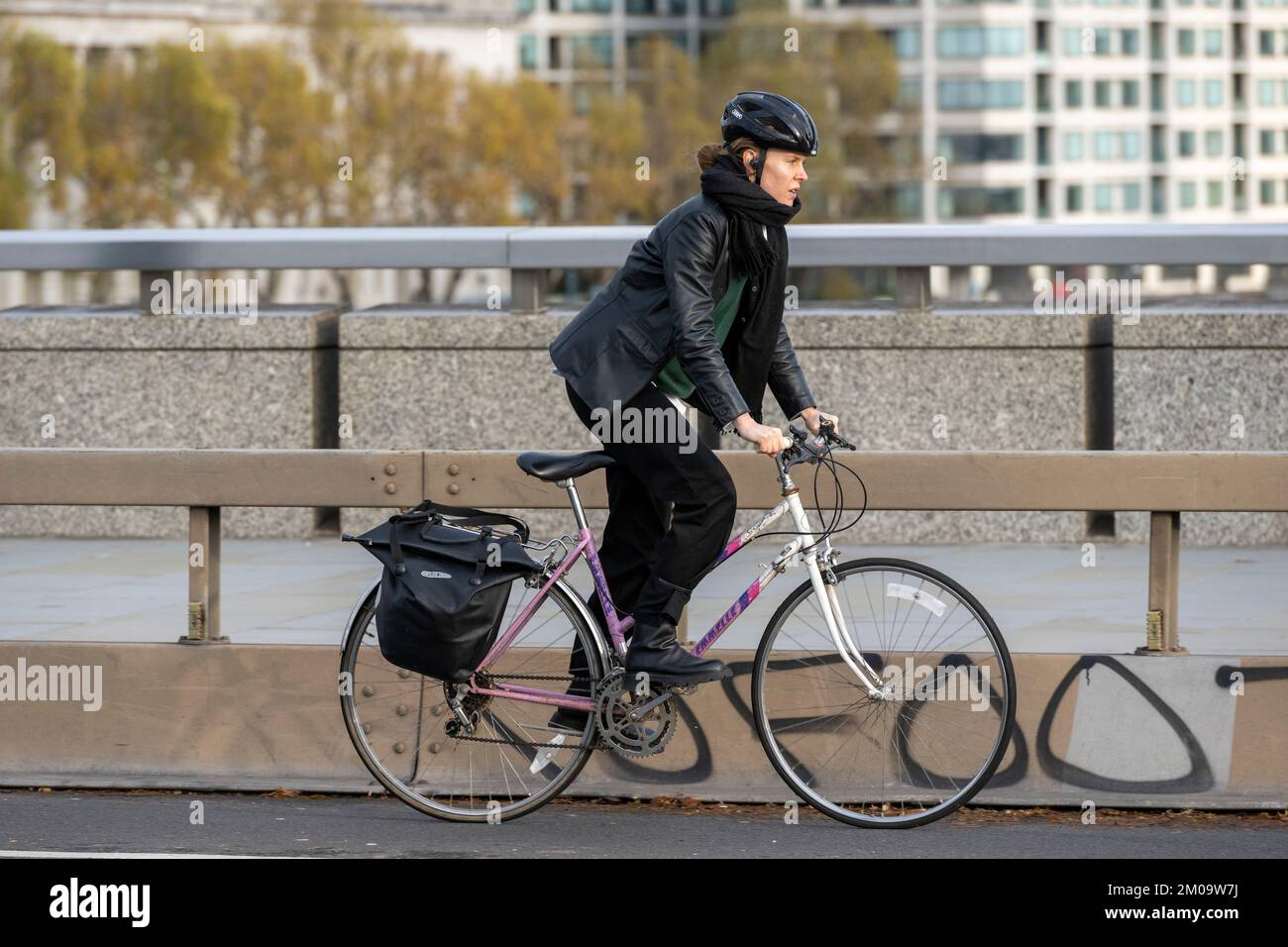 A woman commuting by bicycle during rush hour across, London Bridge, London, UK. 17 Nov 2022 ...