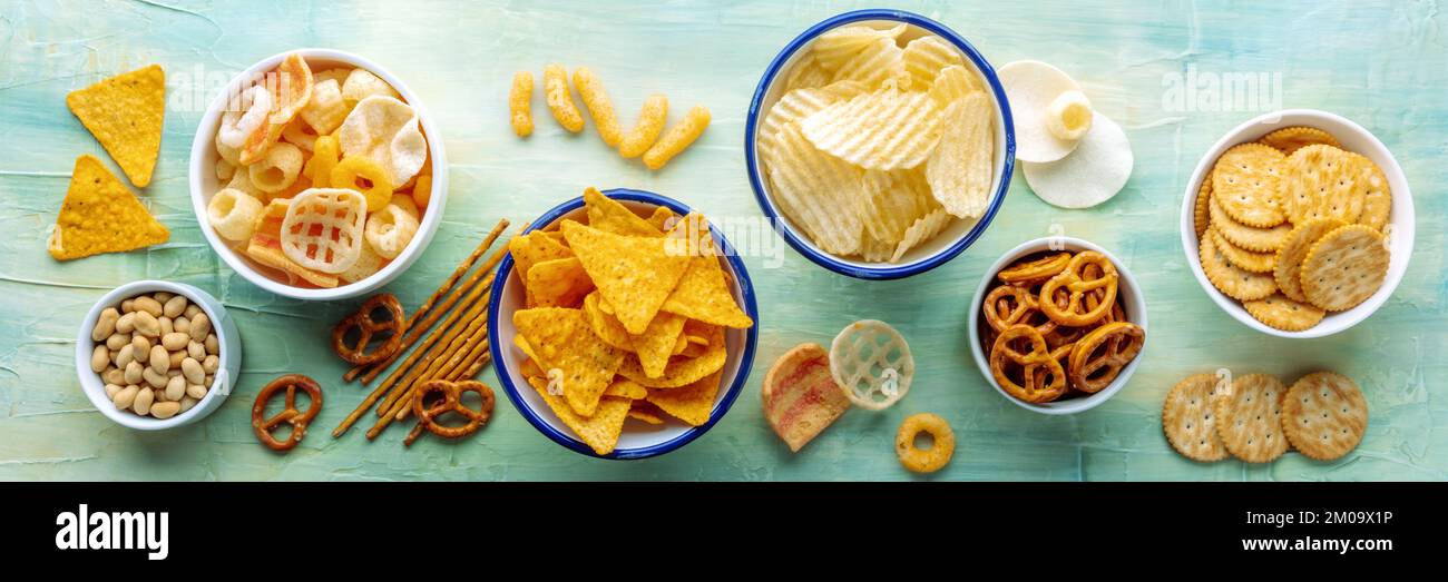 Salty snacks panorama. Party food. Potato and tortilla chips, crackers ...