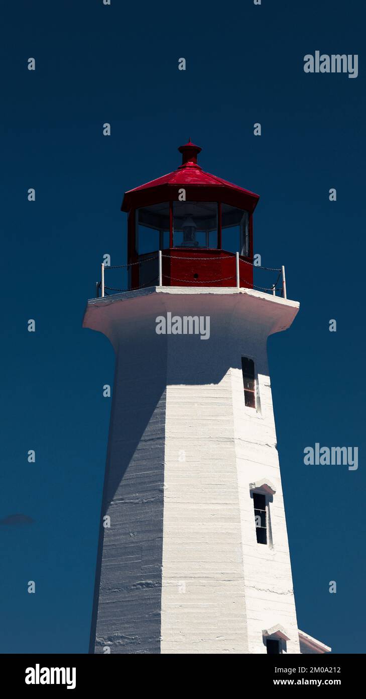 A vertical shot of a white lighthouse with a red top part against the ...