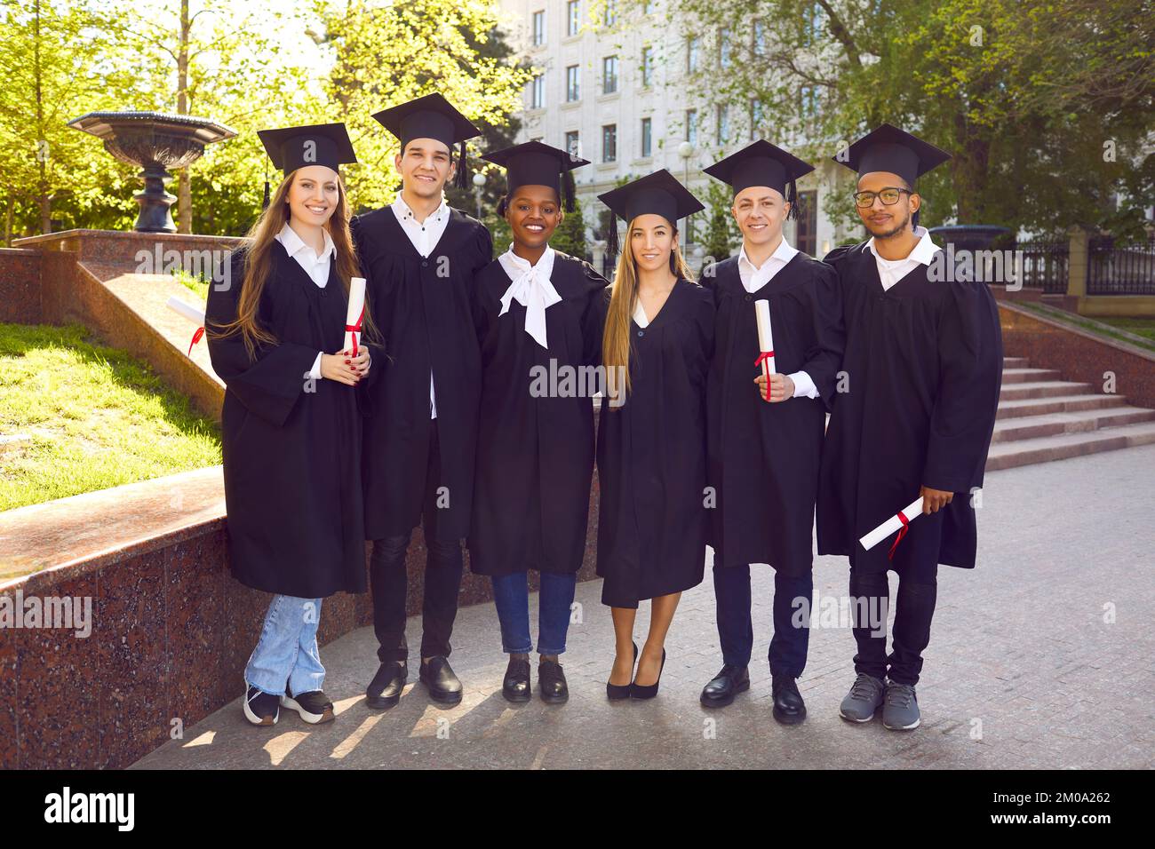 Ready to success. Six college graduates standing in a row and smiling ...