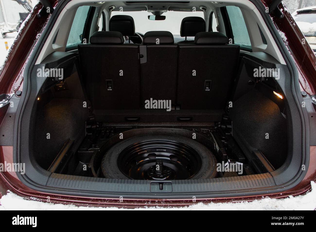Spare wheel in the trunk of a modern car. Jack lifting and a spare tire ...