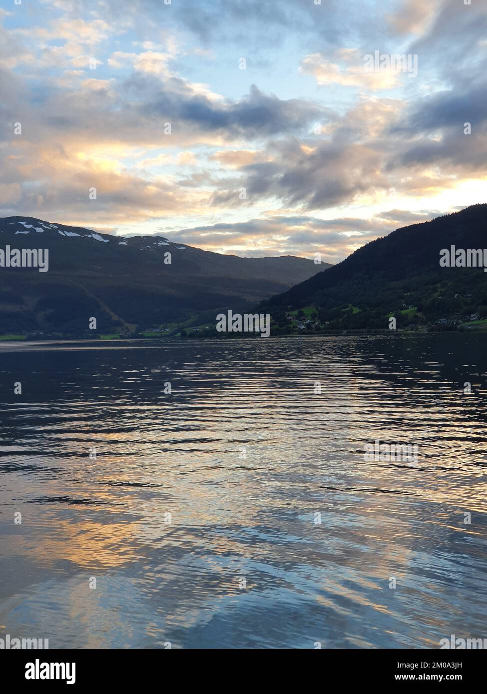 A vertical shot of the cloudy sky over the lake in spring at sunset ...