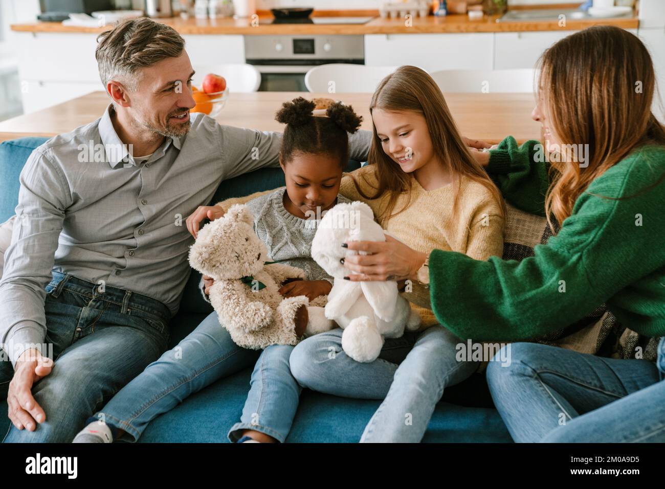 Happy family with adopted african little girl sitting on couch in ...