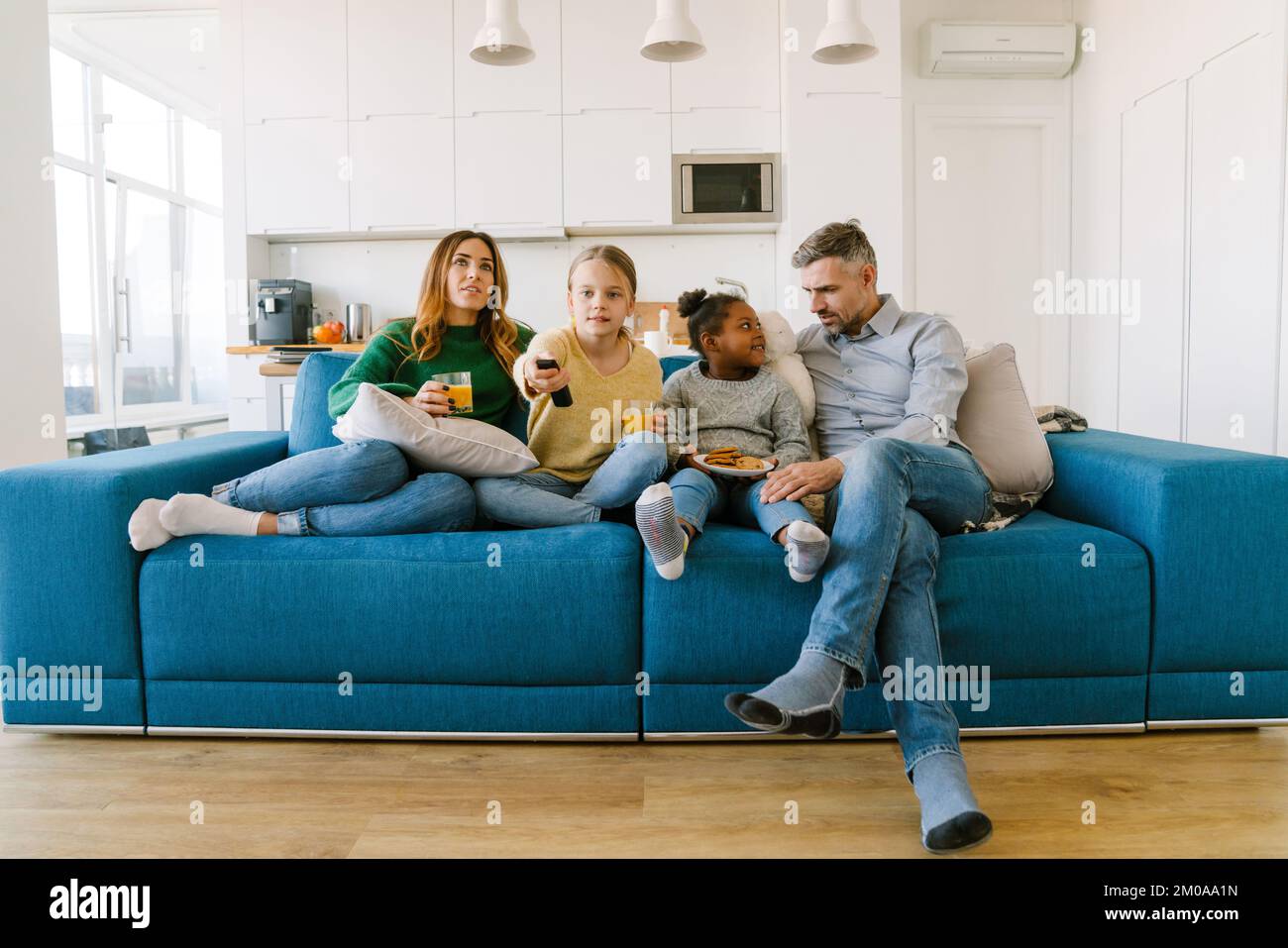 Happy familly mother, father and two daughters sitting on sofa and ...