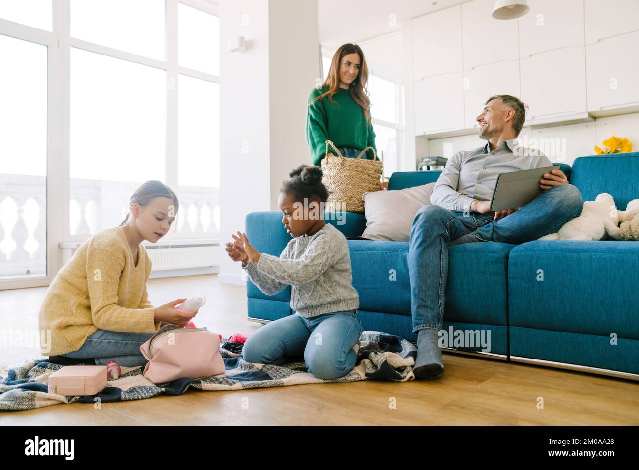 Happy family at home. Mother doing housework, father working on tablet ...