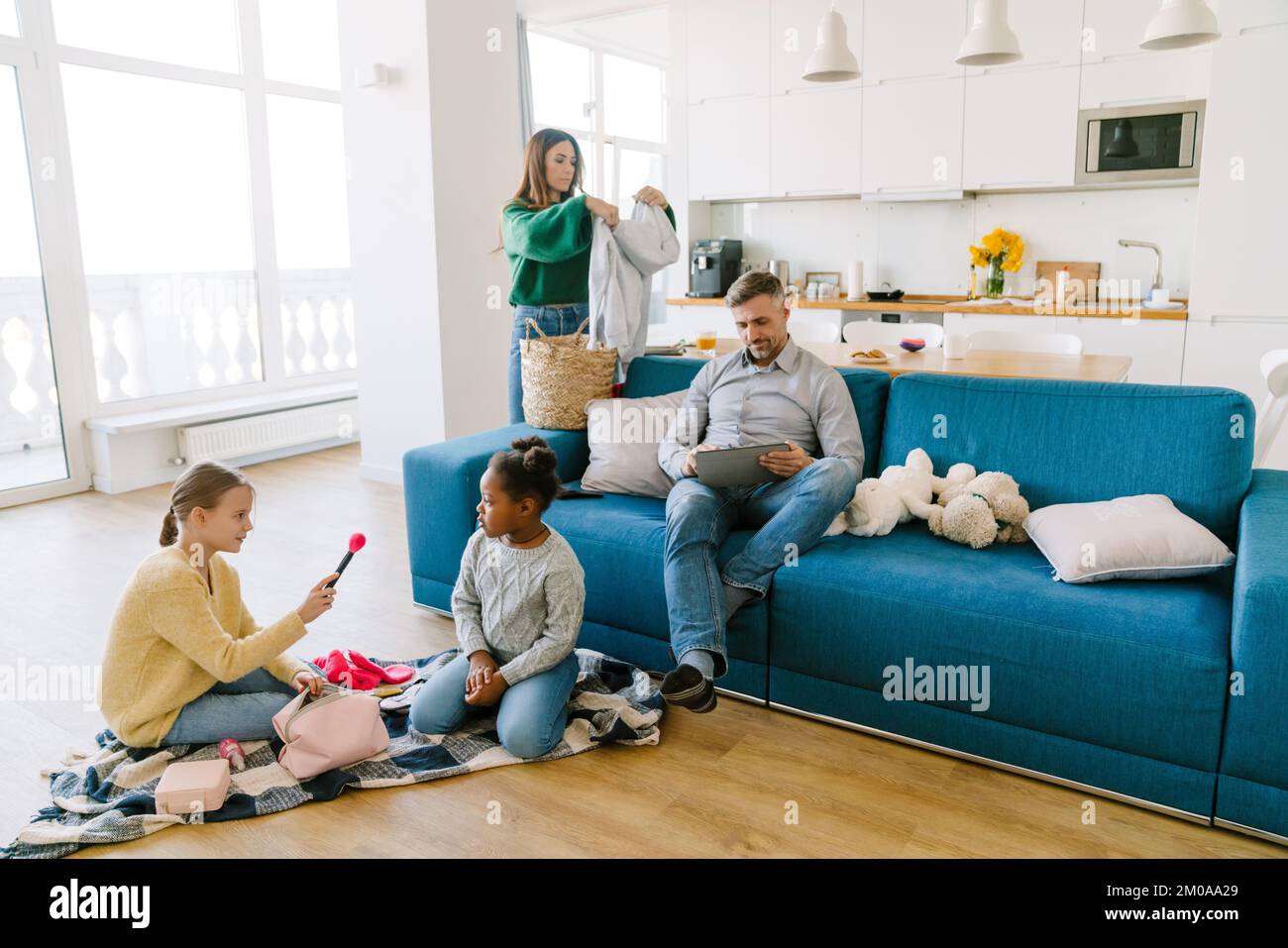 Happy family at home. Mother doing housework, father working on tablet ...