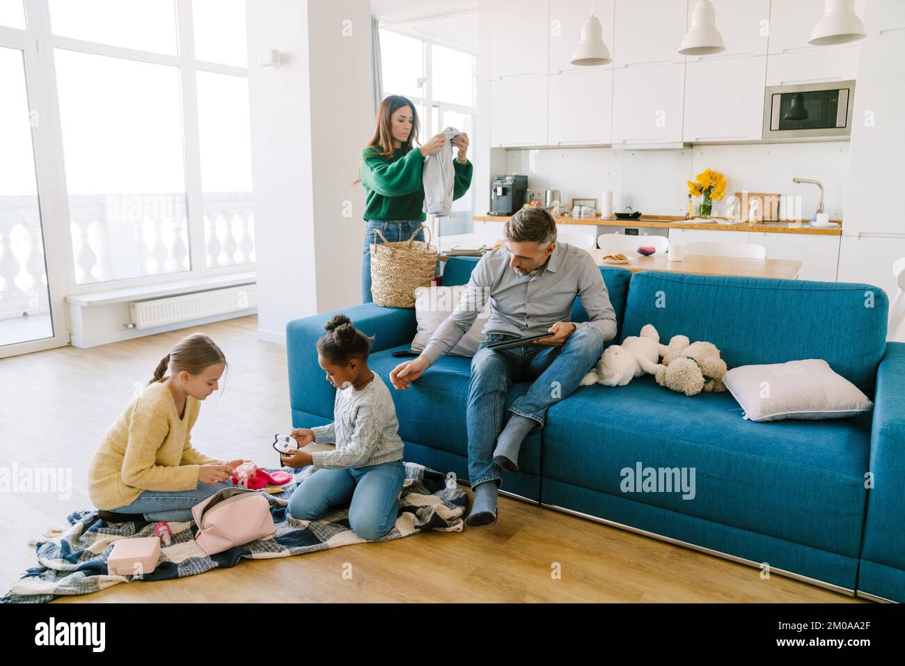 Happy family at home. Mother doing housework, father working on tablet ...