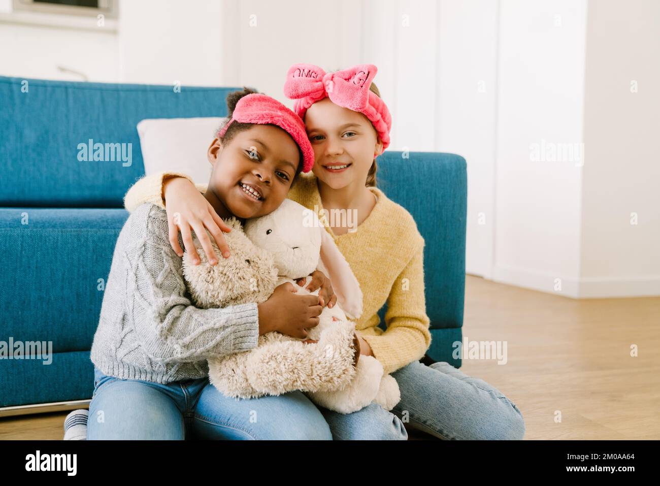 Little smiling happy interracial sisters hugging and playing with ...