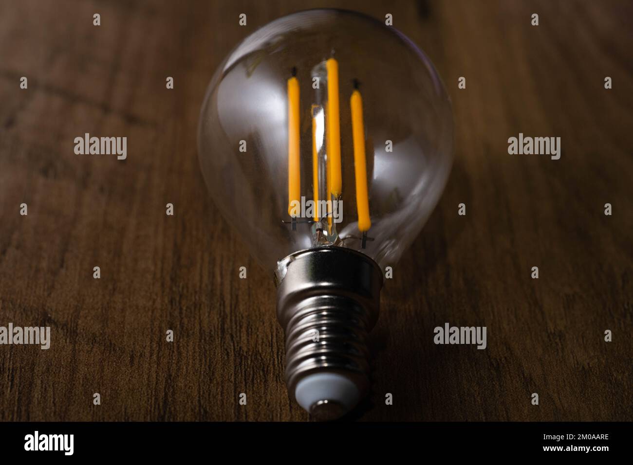 A closeup of a clear light bulb on a wooden surface Stock Photo - Alamy