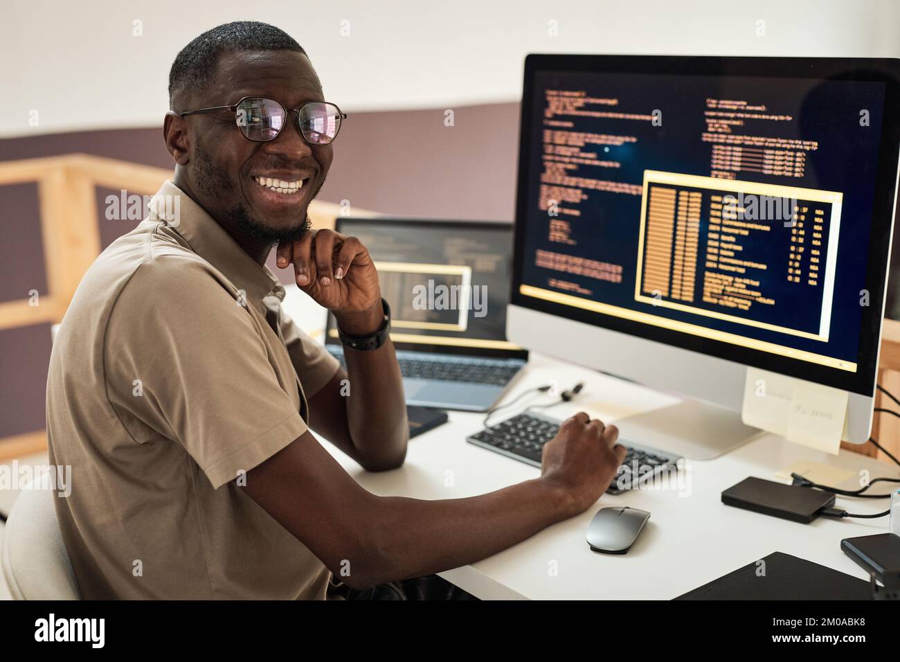 Portrait of joyful software developer in glasses programming on ...