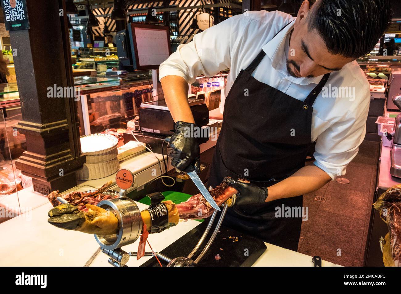 Spain, Madrid, Mercado de San Miguel, Butcher cutting Serrano ham Stock ...