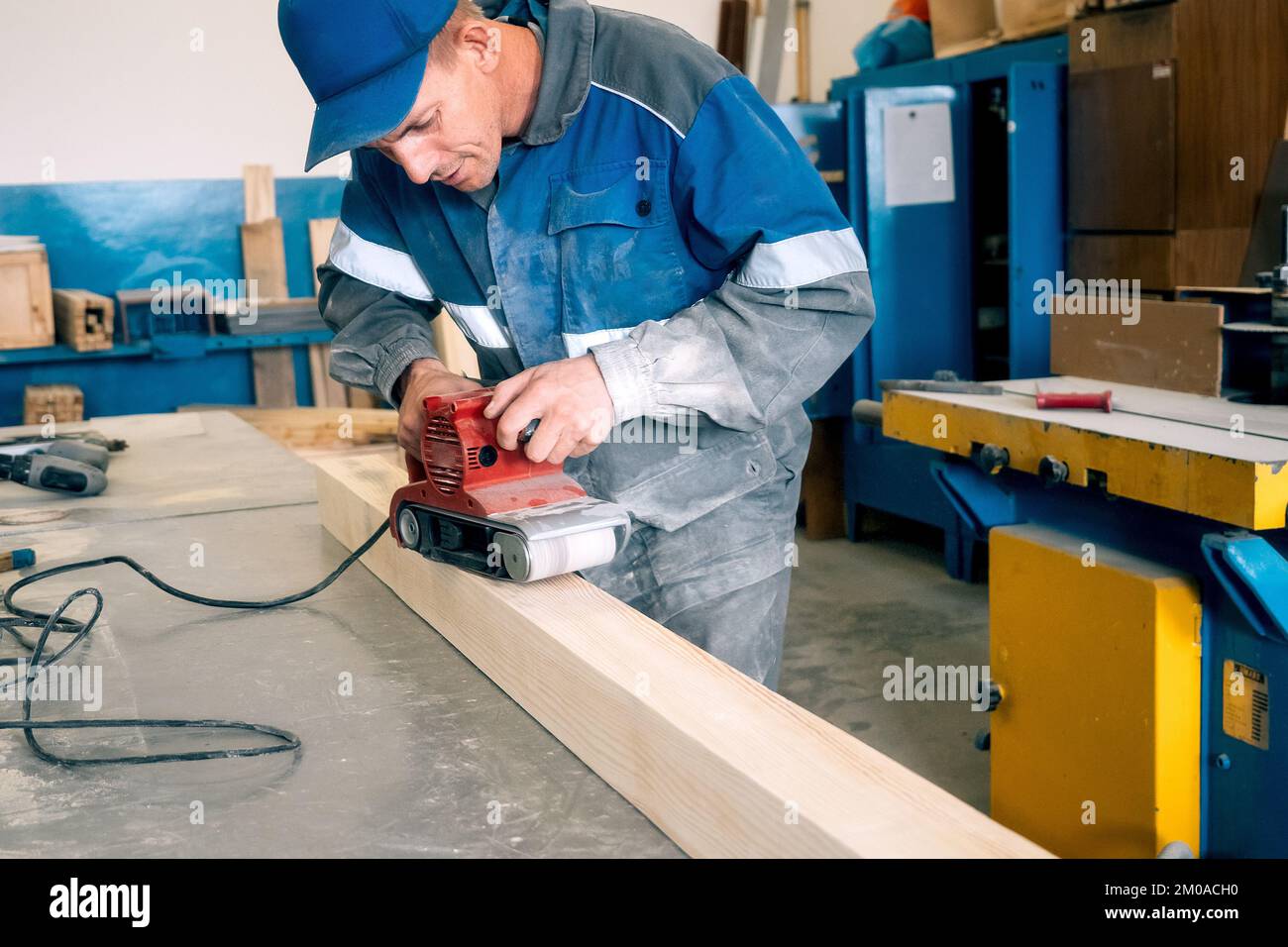 Professional woodworker grinds wooden bar on workbench in carpentry ...