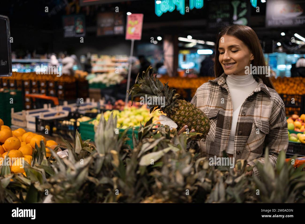 Female grocery store customer buys pineapples in the fruit department ...