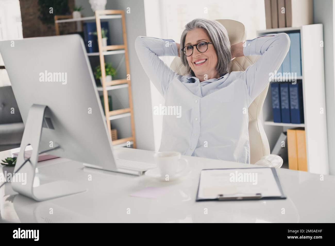 Portrait of positive company owner aged lady sitting chair arms behind ...