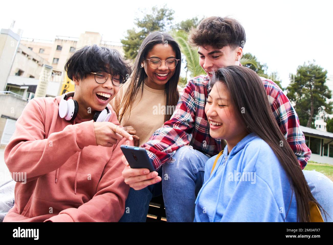 Group of happy students outside the school using mobile phone having ...