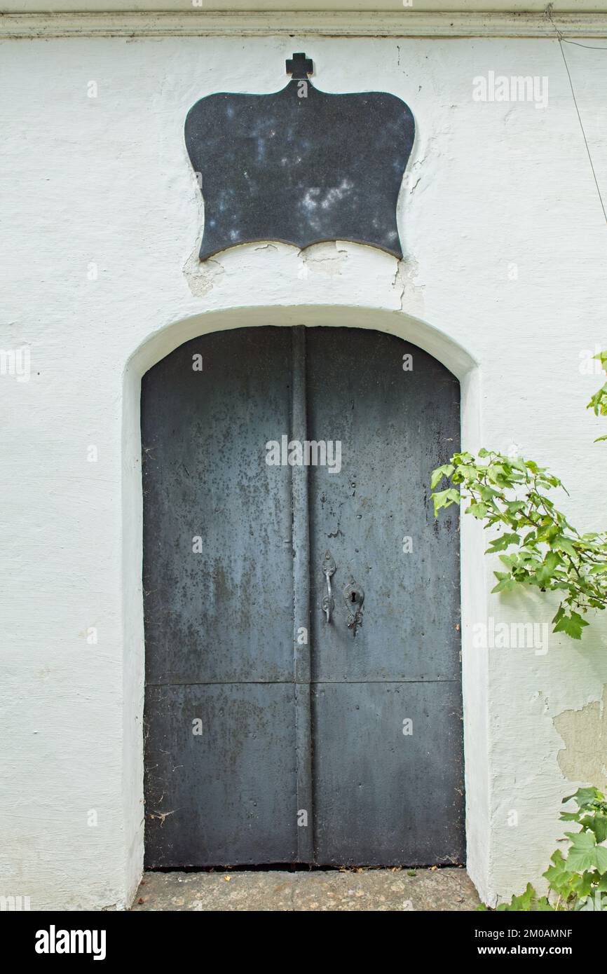 Weathered metal door to an old crypt with white plastered wall Stock ...