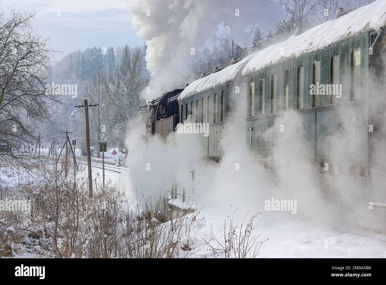 A train pulled by a steam locomotive travels over the snowy winter ...