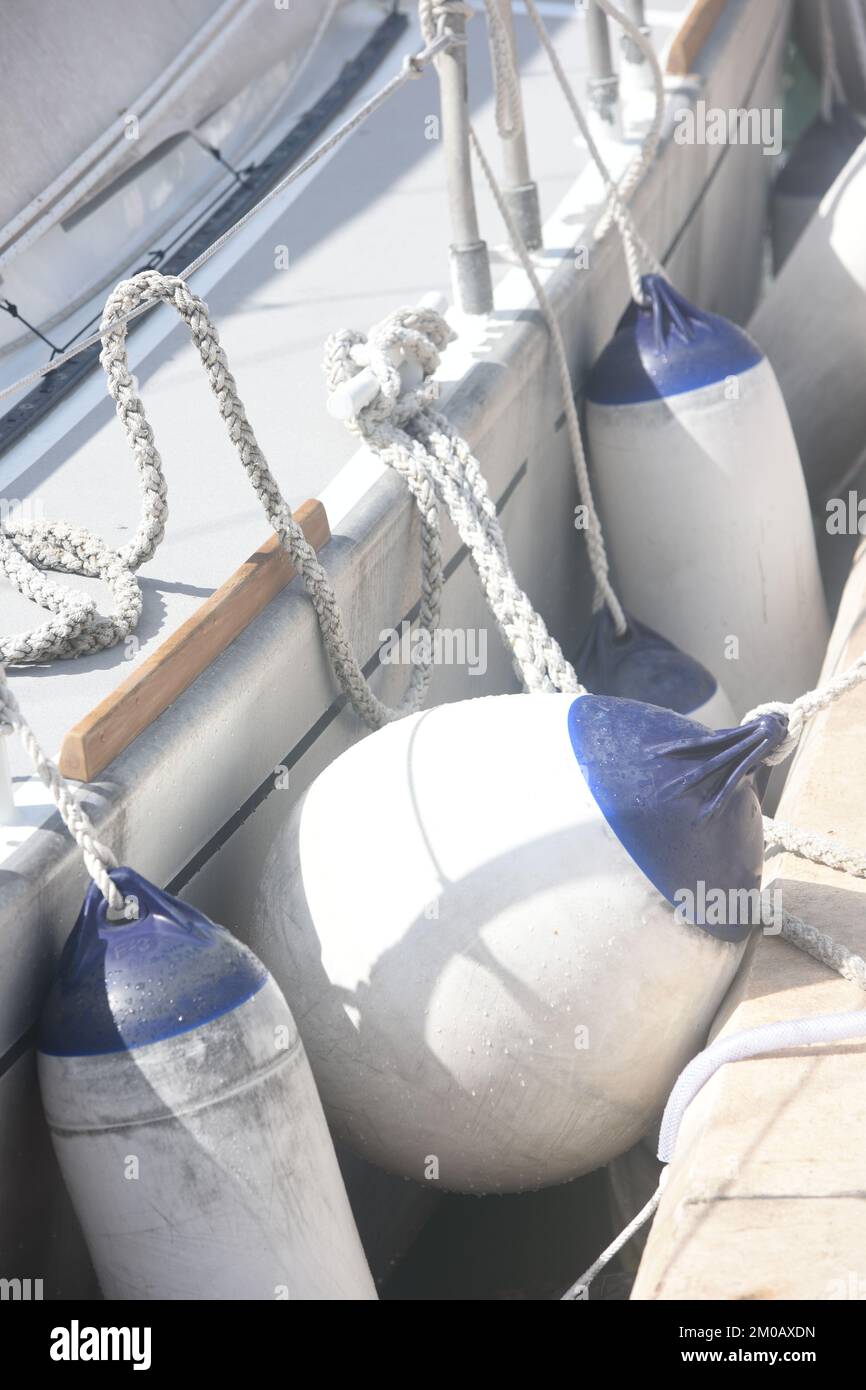 Detail of white fenders suspended between a boat and the dock for ...