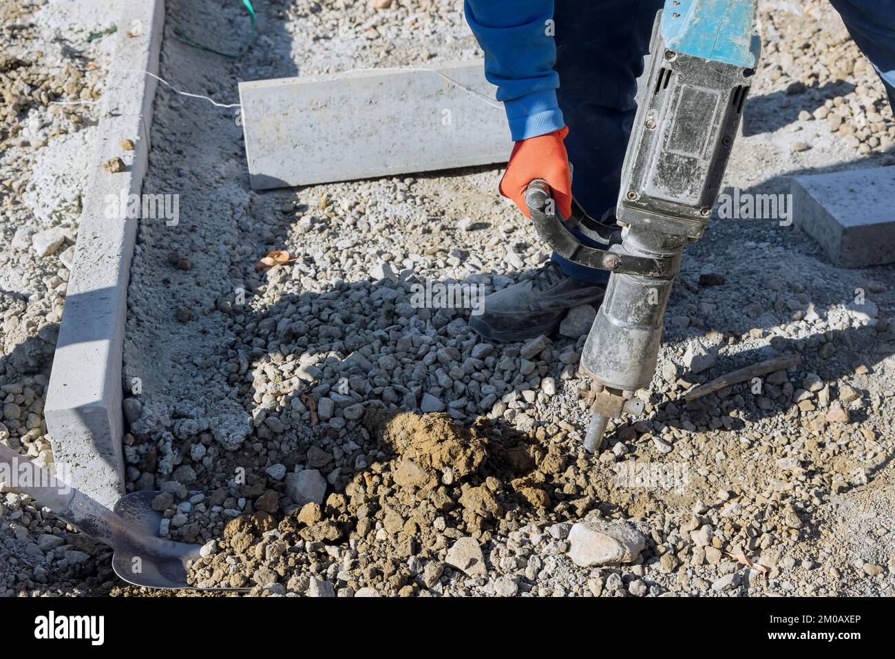 Worker digging and drilling concrete surfaces using jackhammer as part ...