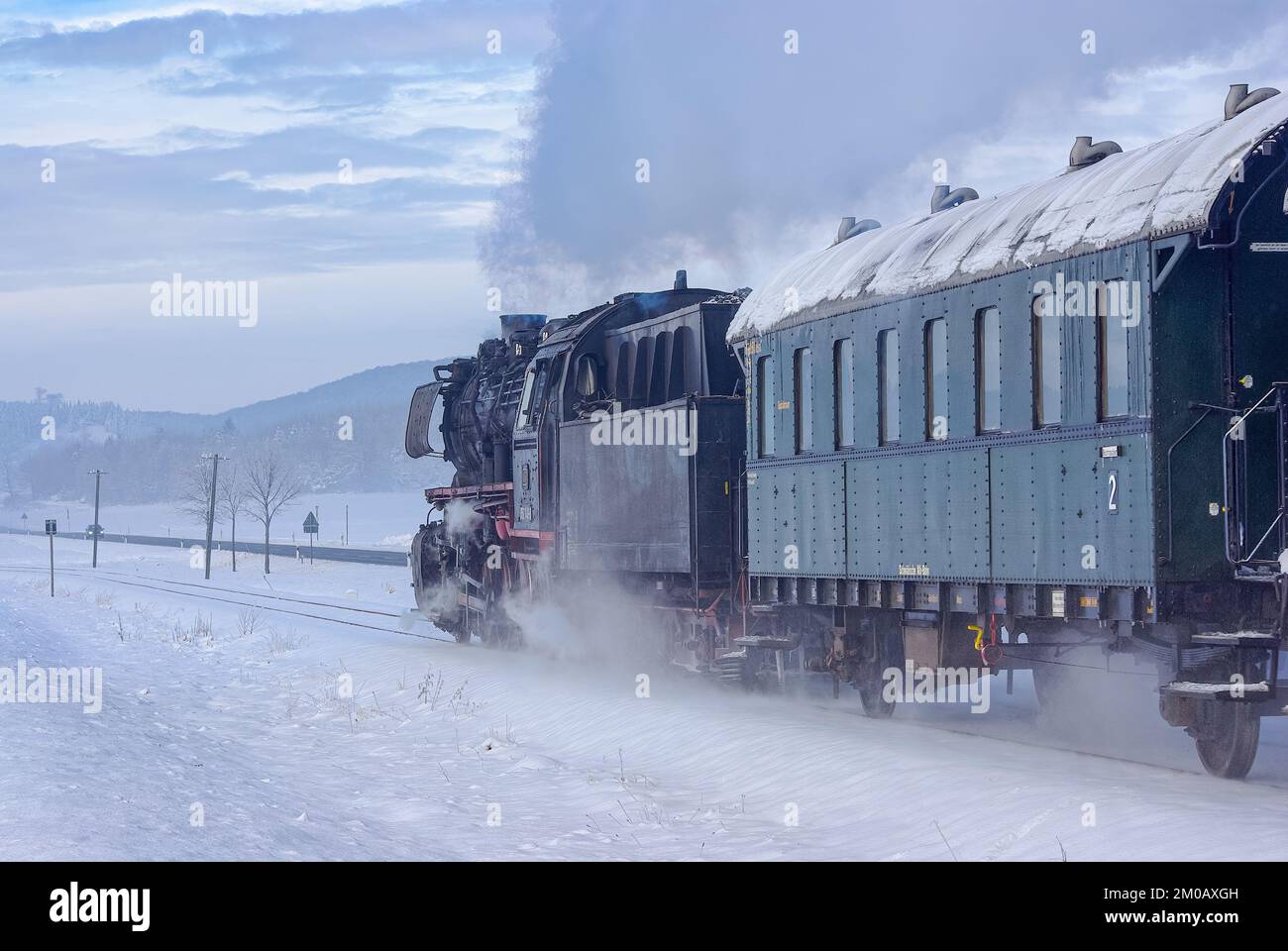 A train pulled by a steam locomotive travels over the snowy winter ...