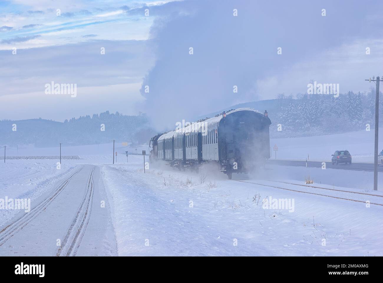 A train pulled by a steam locomotive travels over the snowy winter ...